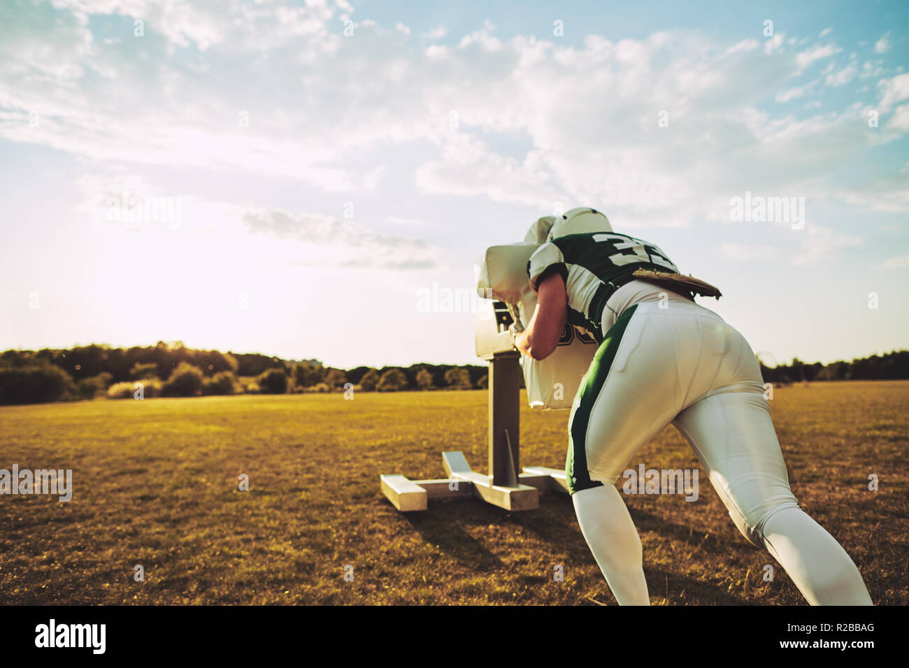 American football player practicing tackling with a tackle sled outside ...