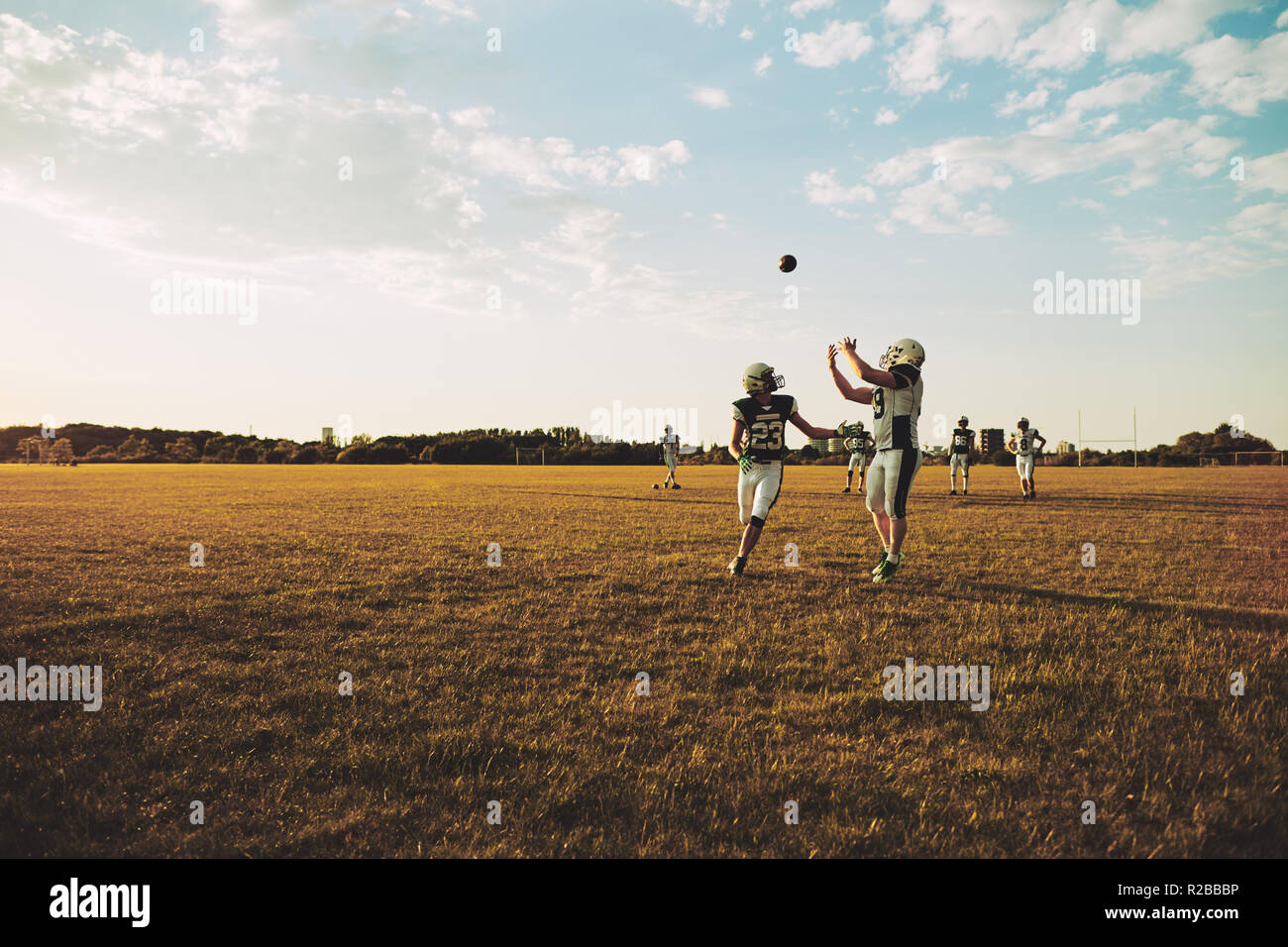 American football player running to catch a pass during team practice ...