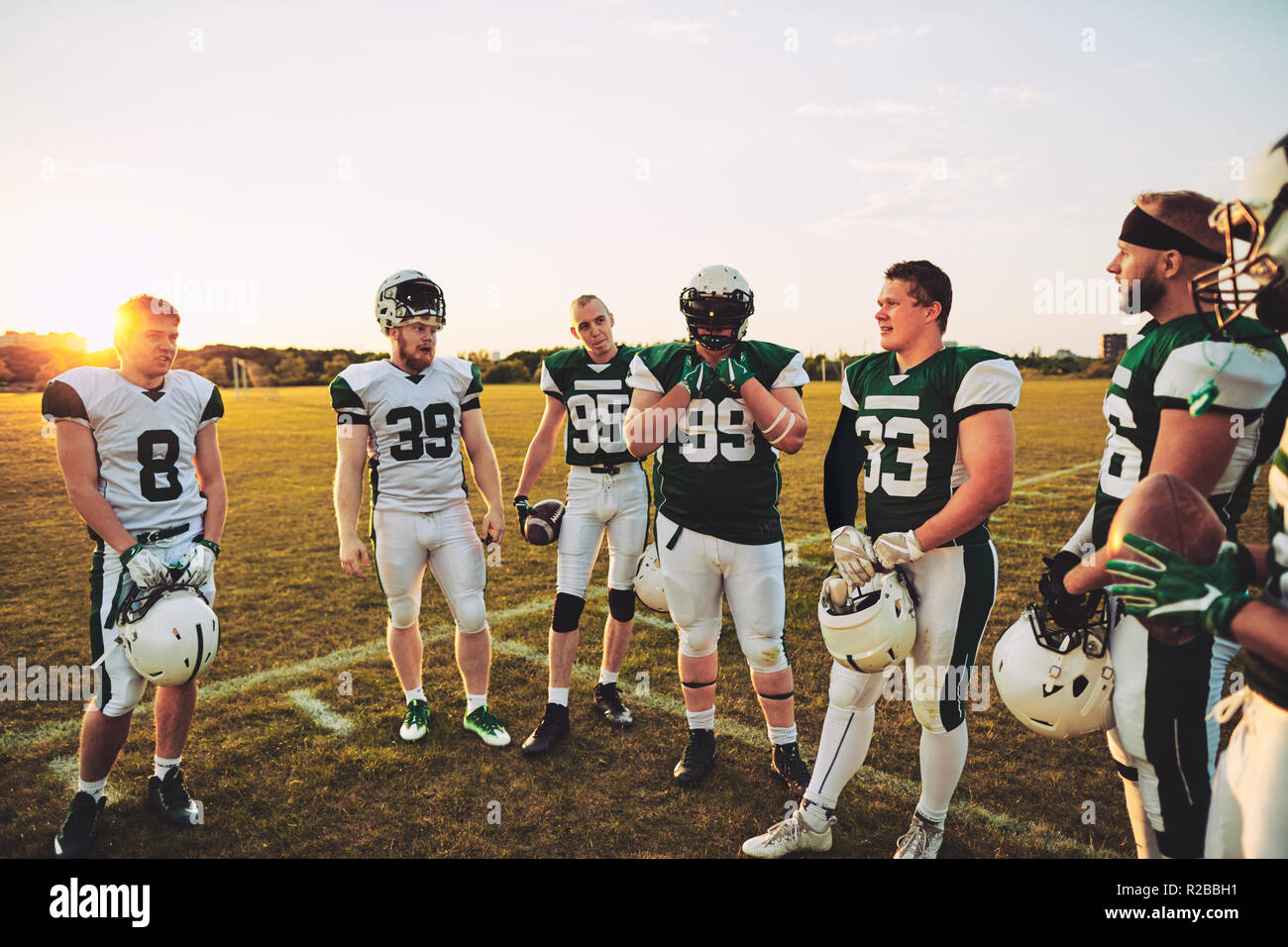 Group of young American football players talking together while ...