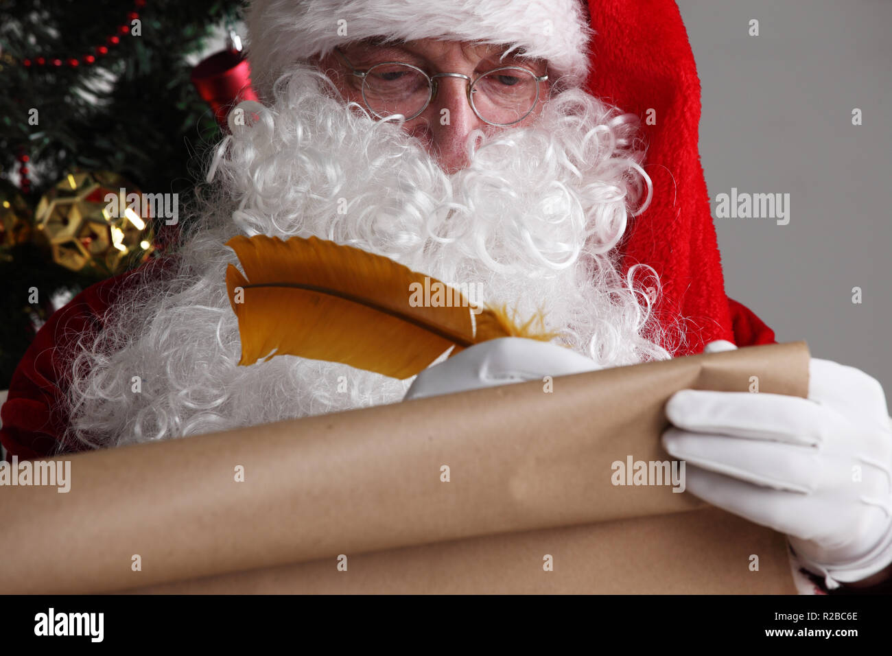 Santa Claus sitting at home and writing on old paper roll to do list ...