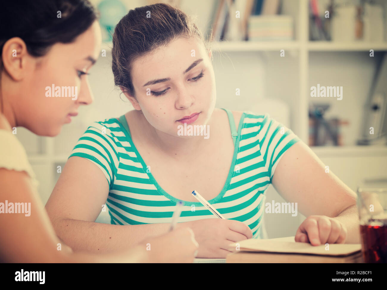 Teens girls studying together at home, doing homework and discussing ...