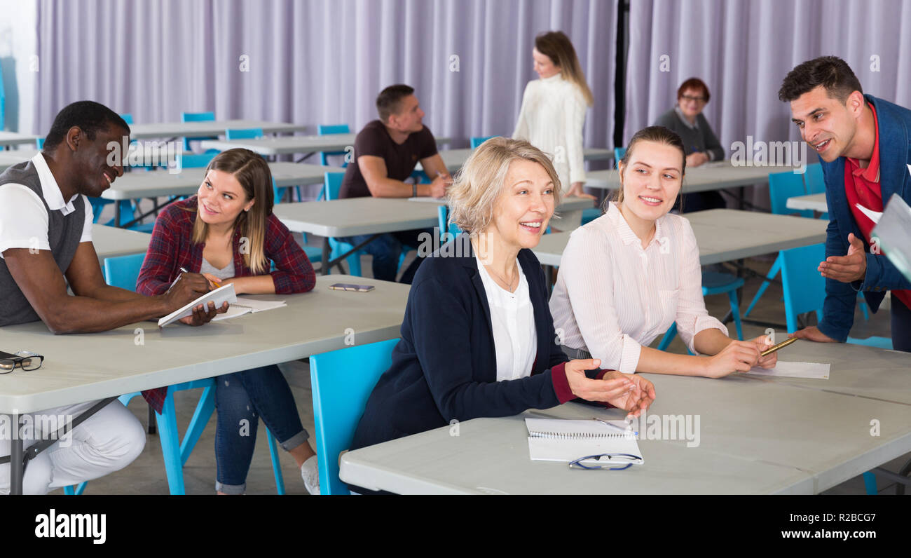 Group of adult education students studying together in class ...