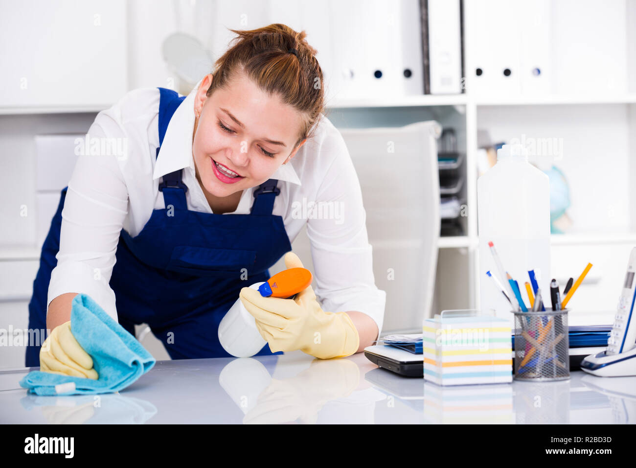 Happy housekeeper is cleaning dust from the desk in the office Stock ...