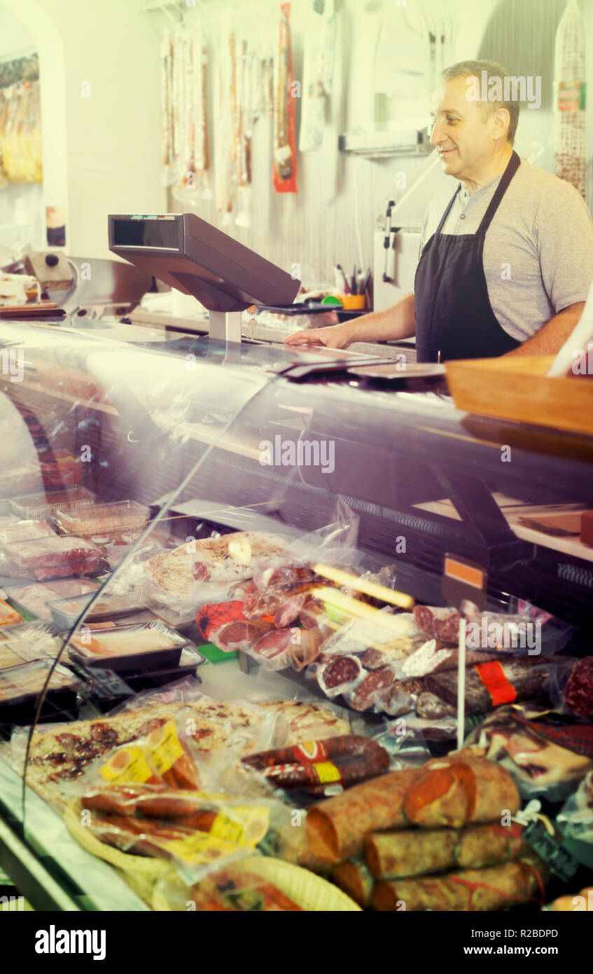 Mature male butcher with wurst and smoked meat at butchery Stock Photo ...