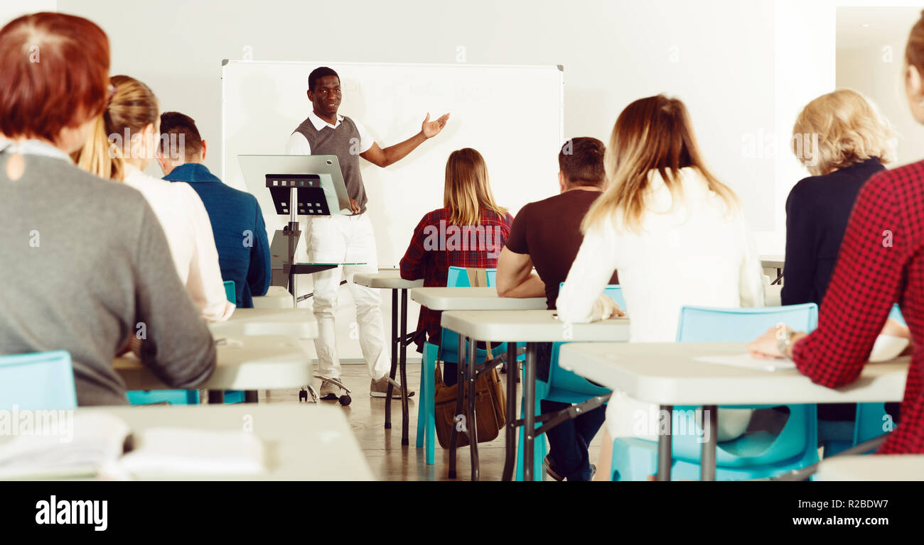 Friendly African American man lecturing to attentive adult students at ...