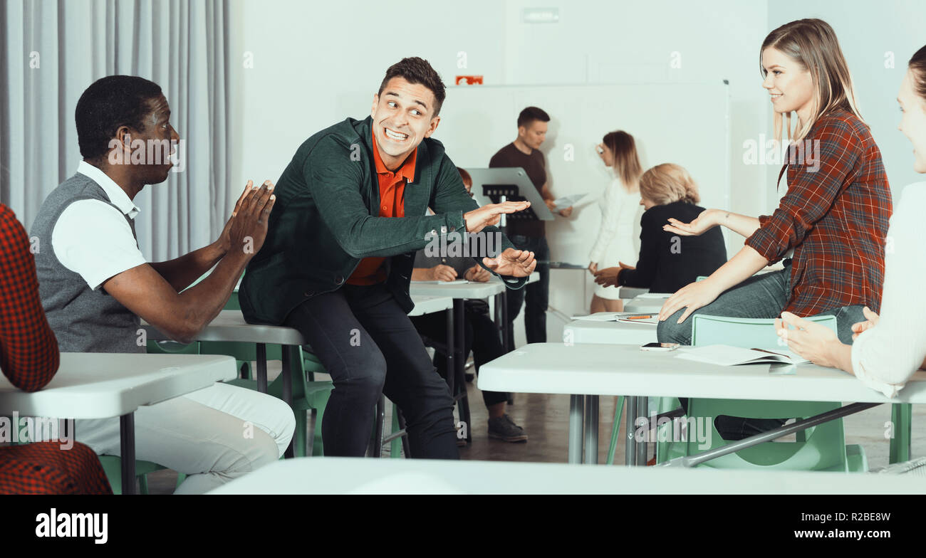 Happy group of adult students lively chatting while enjoying free time ...