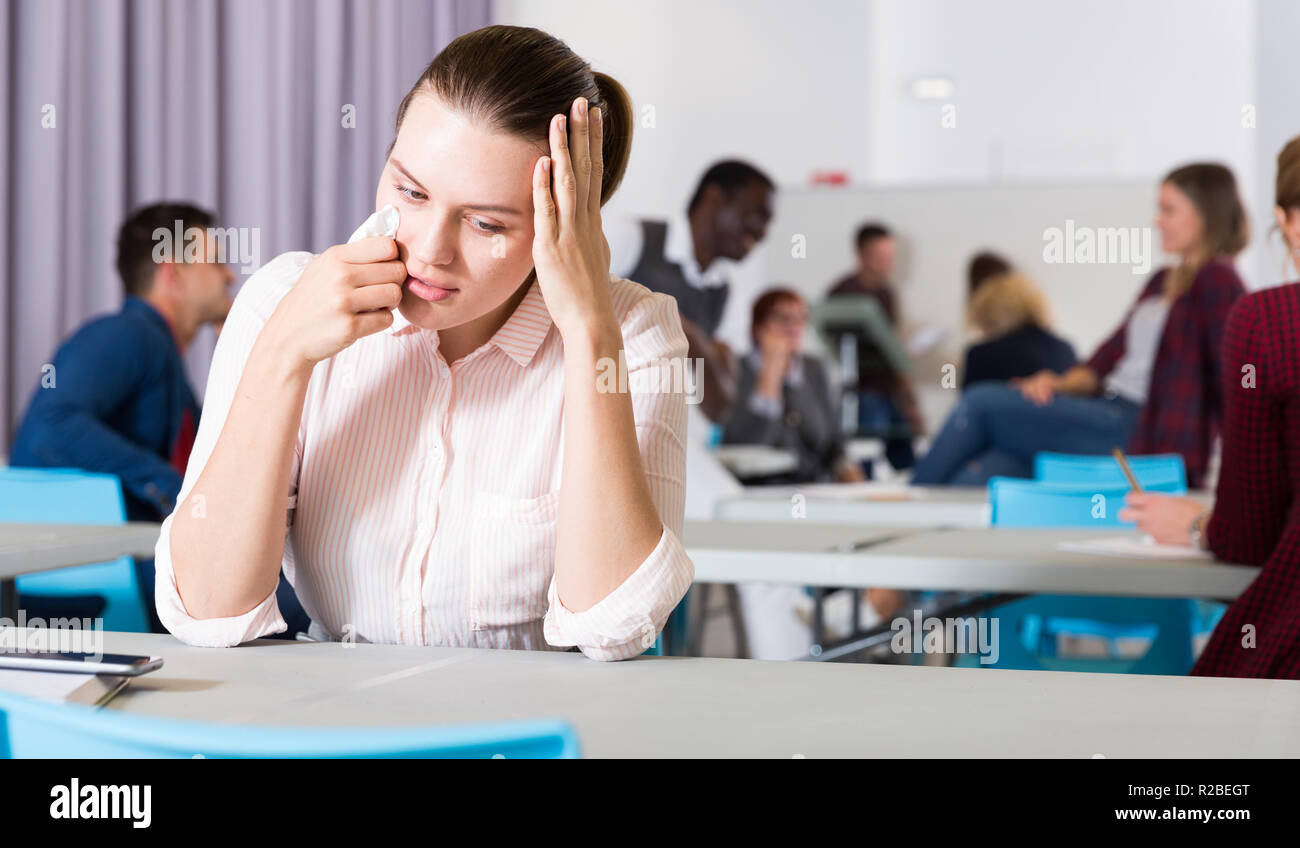 Portrait of unhappy girl sitting apart in class, having conflict with ...