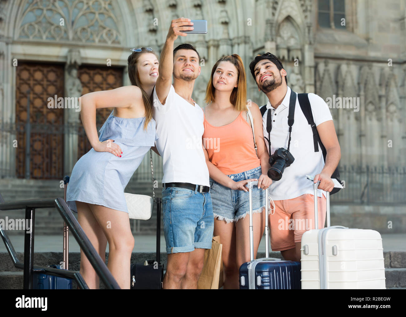Four glad travellers smiling and making selfie with mobile phone Stock ...