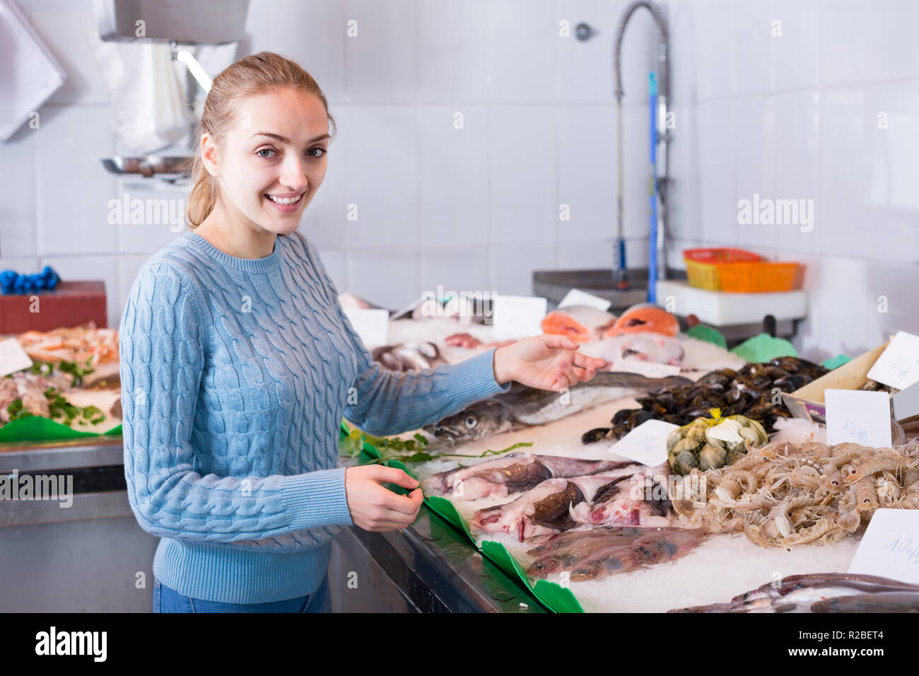 Smiling female customer buying fish and chilled seafood in shop Stock ...