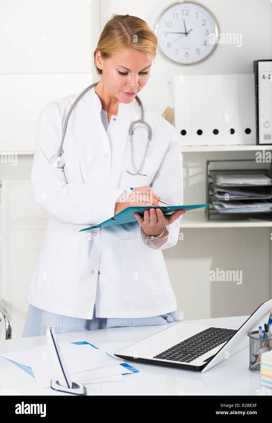 portrait of young germany positive female medic with clipboard in ...