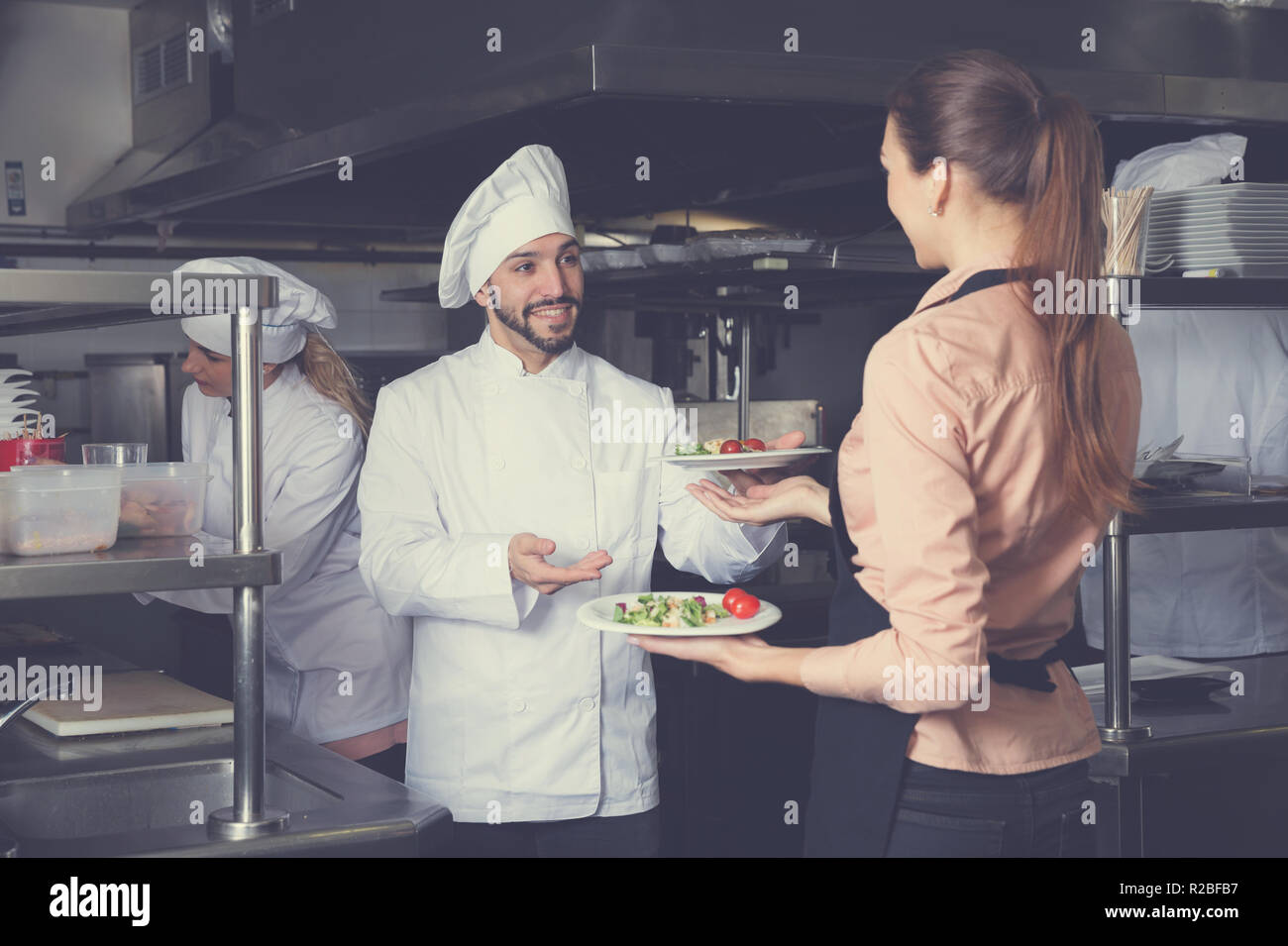 Head chef checking dishes in kitchen of restaurant before serving ...