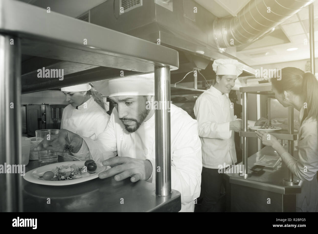 Head chef checking dishes in kitchen of restaurant before serving ...
