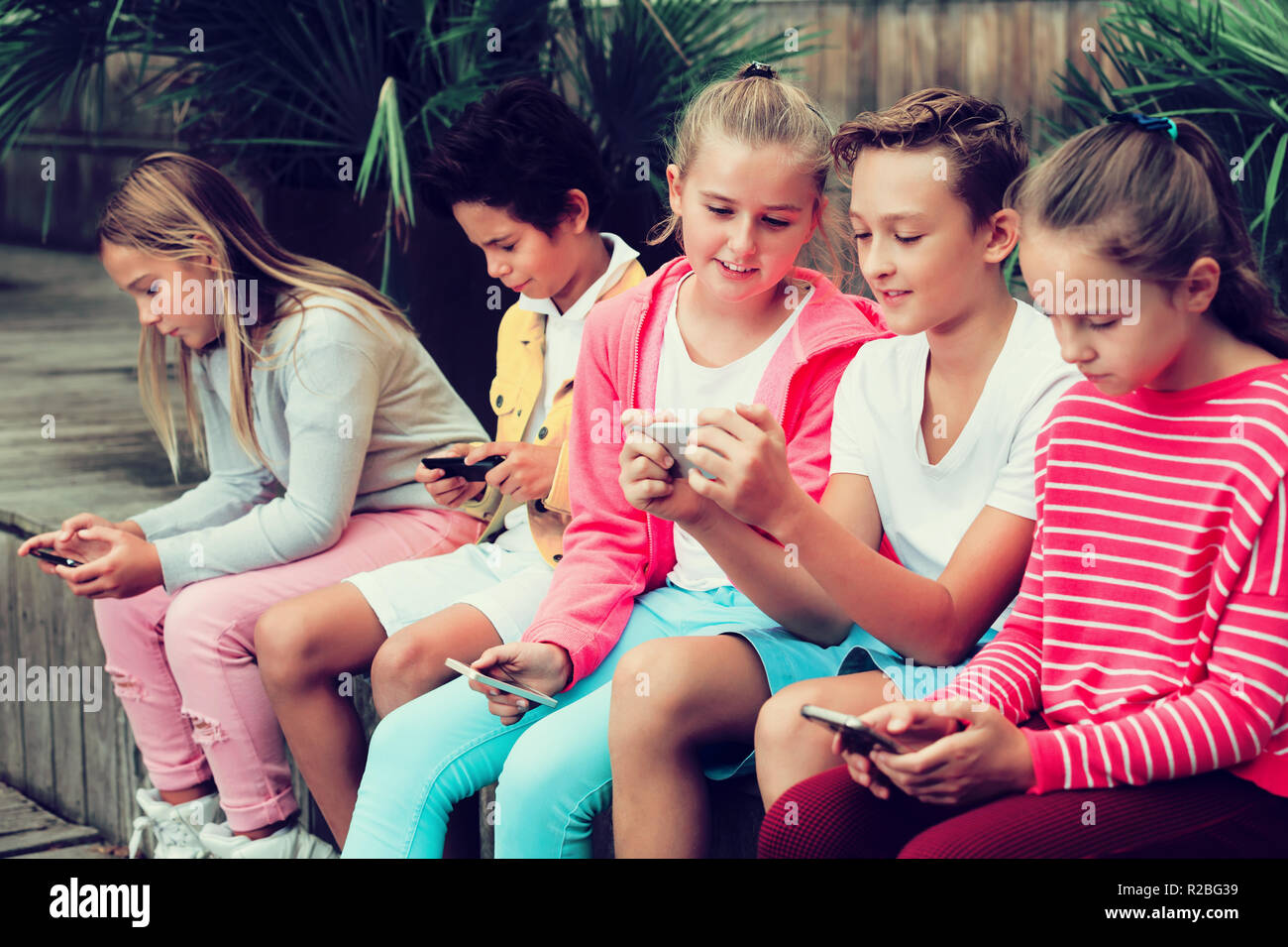 Positive children are playing on smartphone in the playground Stock ...