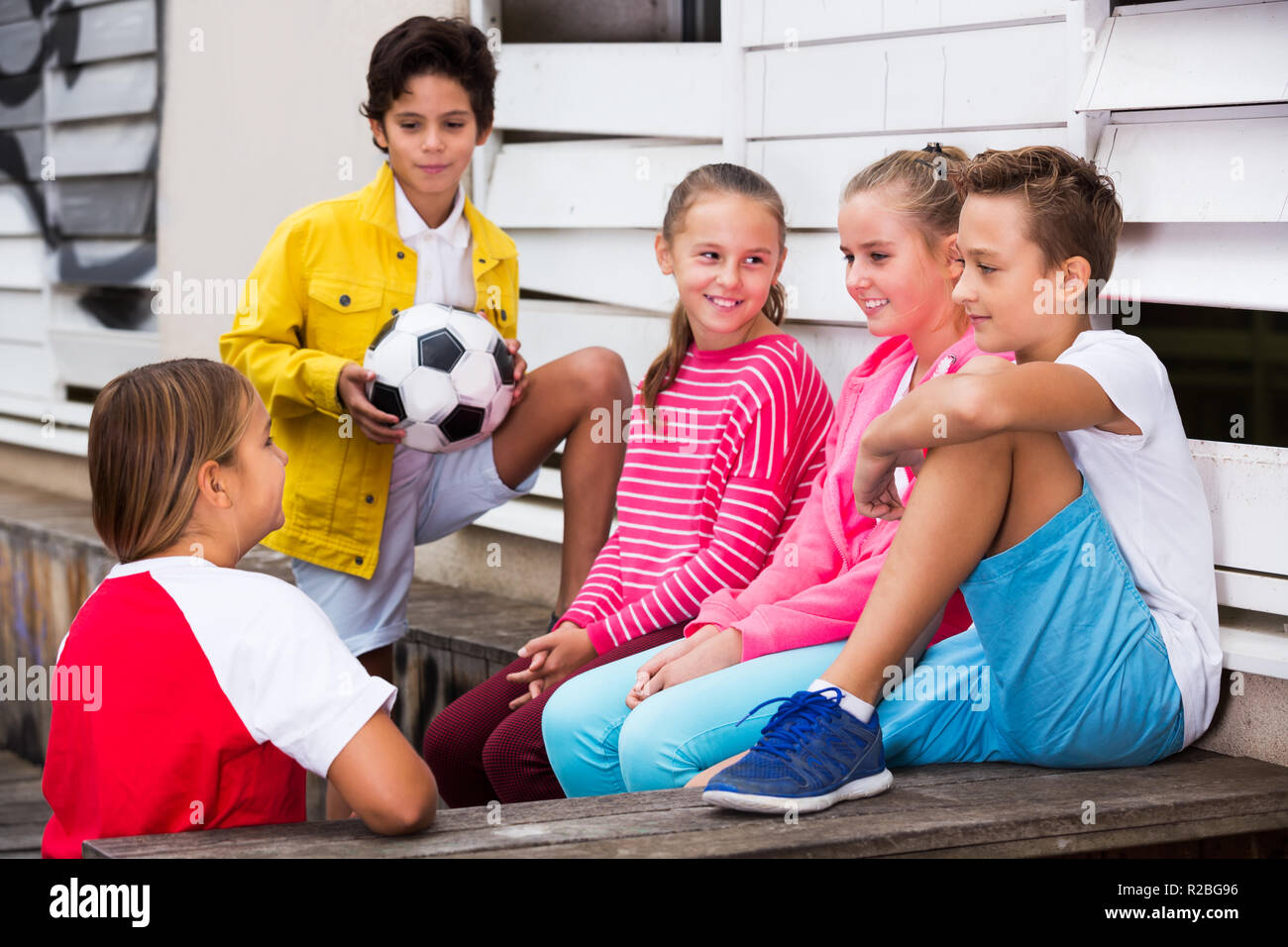 Five kids are talking about play on walk on city street Stock Photo - Alamy