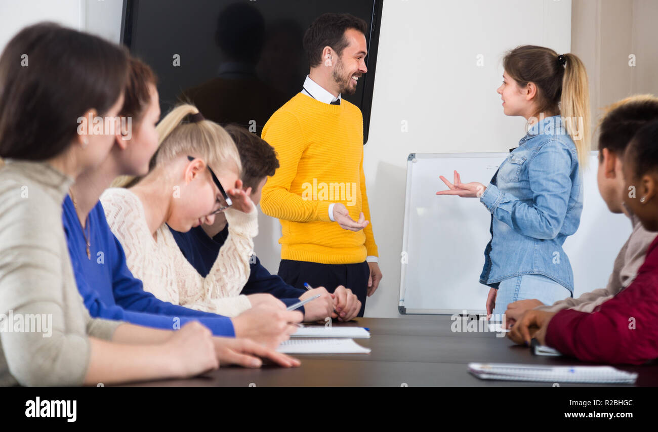 Female student is giving answer to teacher’s question at writing board ...