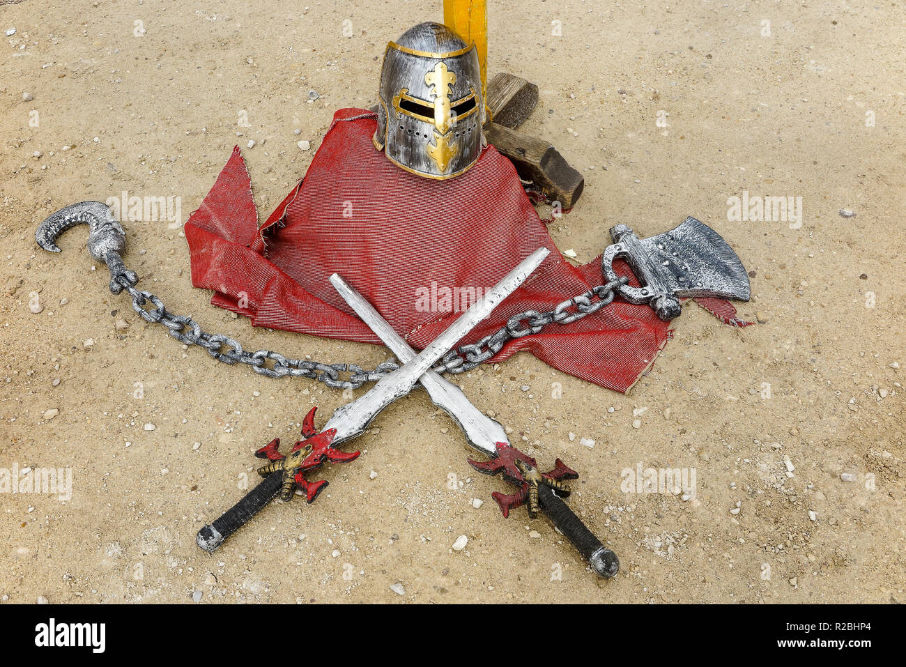 still life with medieval helmet, swords and chain on a floor of sand ...
