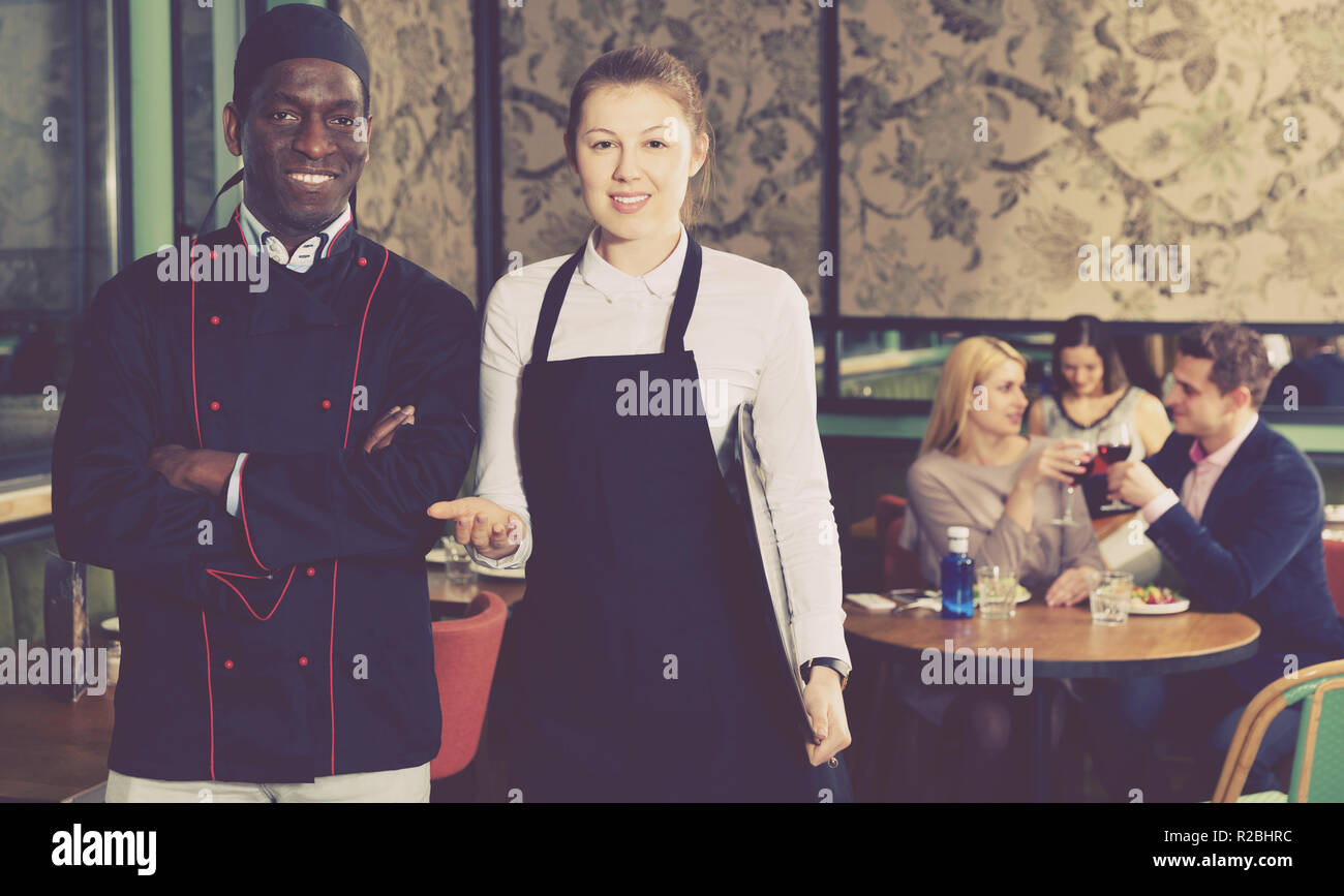 Polite happy cheerful positive waitress standing in restaurant hall ...