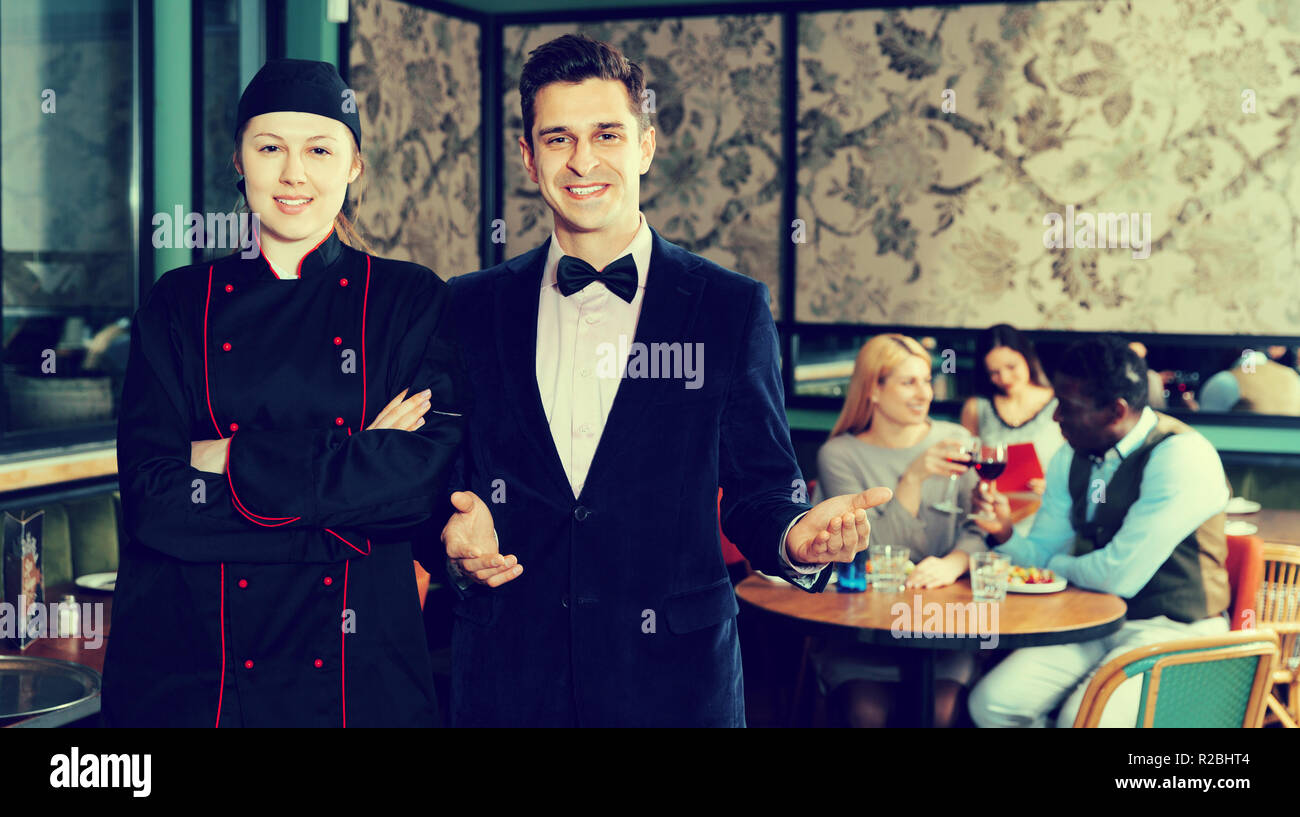 Confident female chef standing in restaurant hall with elegant cheerful ...