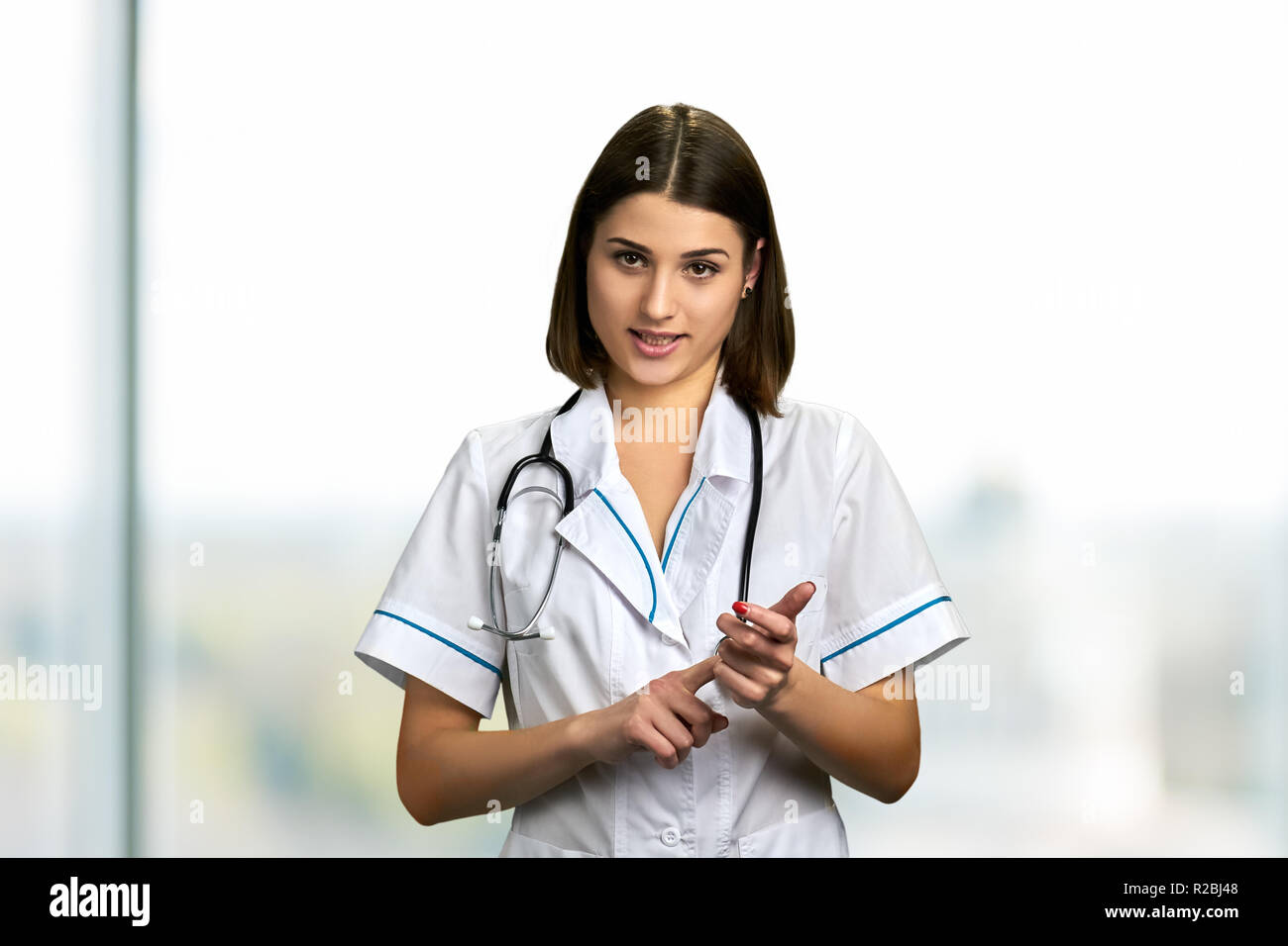 Female doctor talking to camera. Pretty doctor in white coat with ...