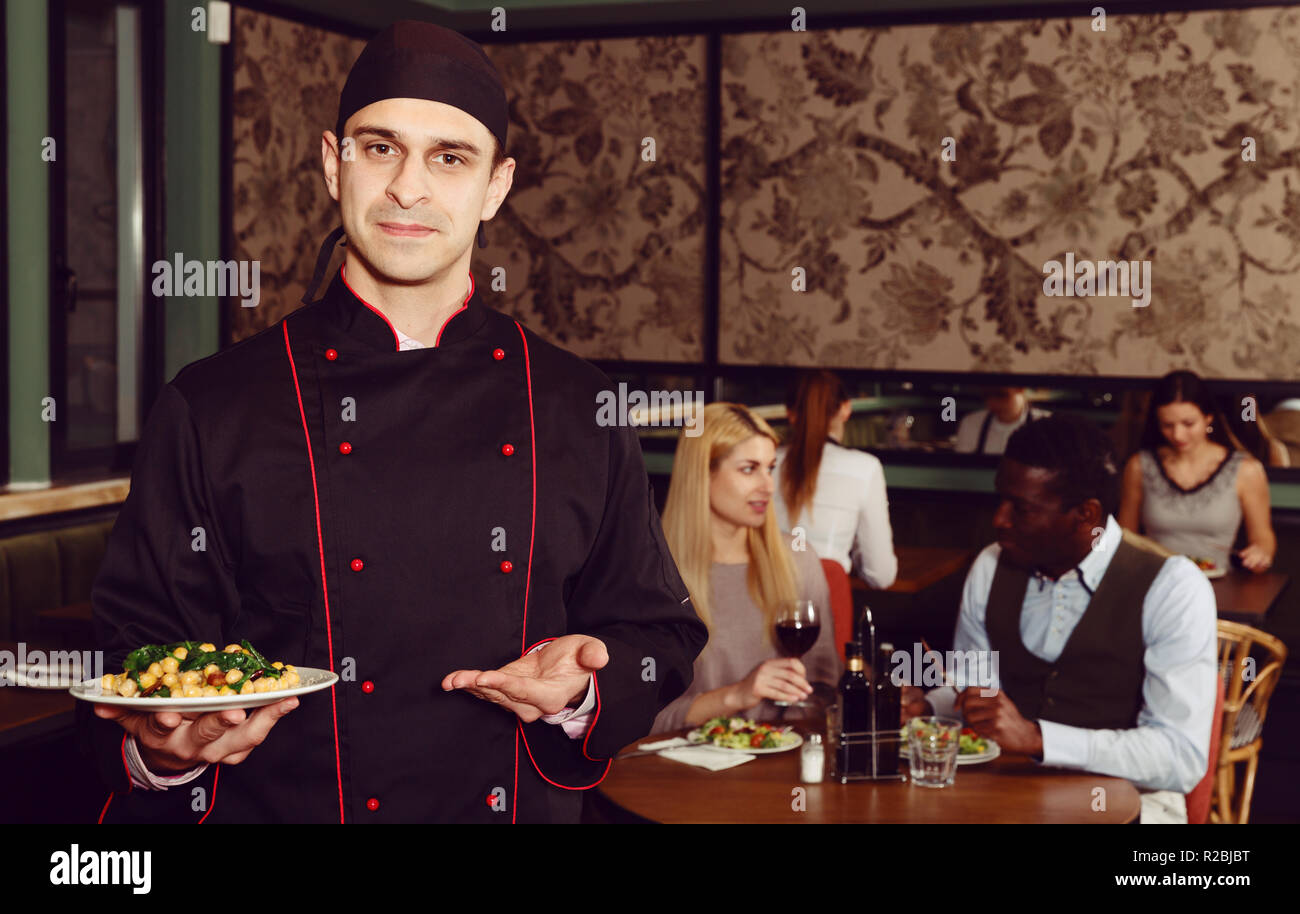 Professional chef of modern restaurant inviting to degustation of dish ...