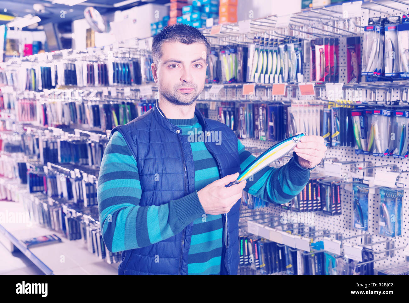 male customer selecting fishing lures near stand in the sports shop ...