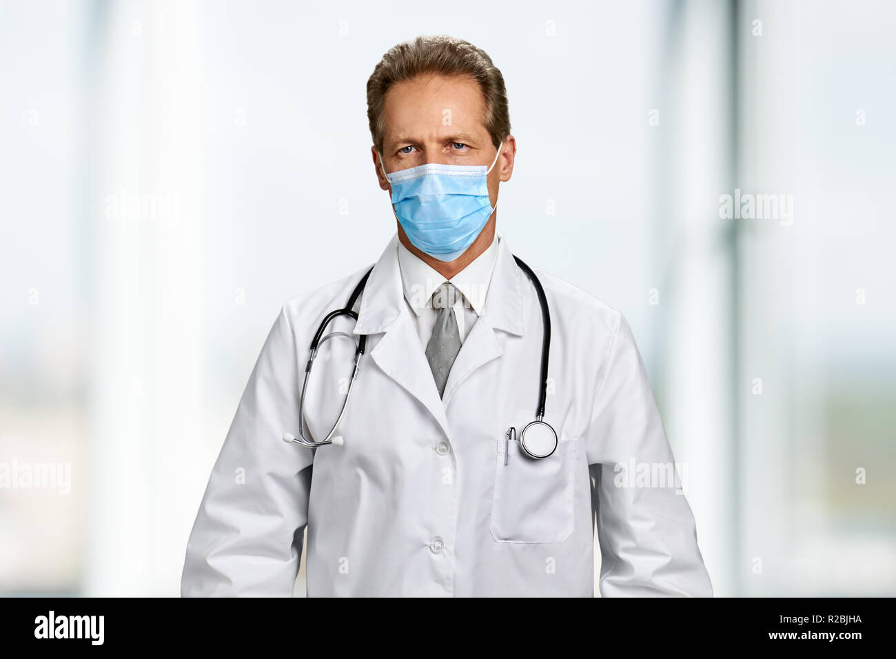 Doctor with face mask and stethoscope. Male caucasian doctor wearing ...