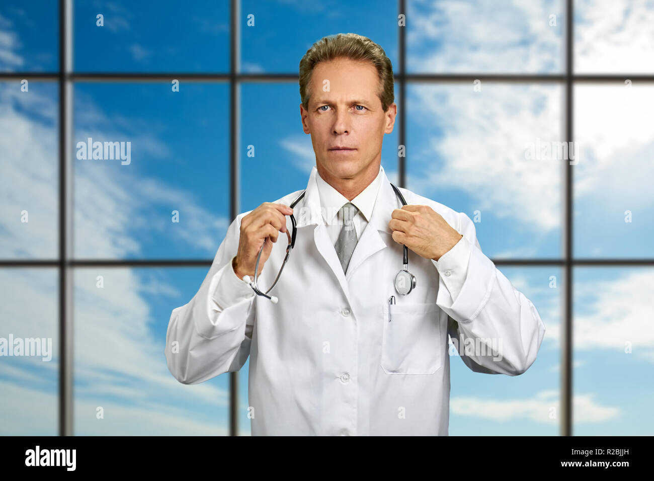Confident doctor adjusting his stethoscope. Portrait of male caucasian ...