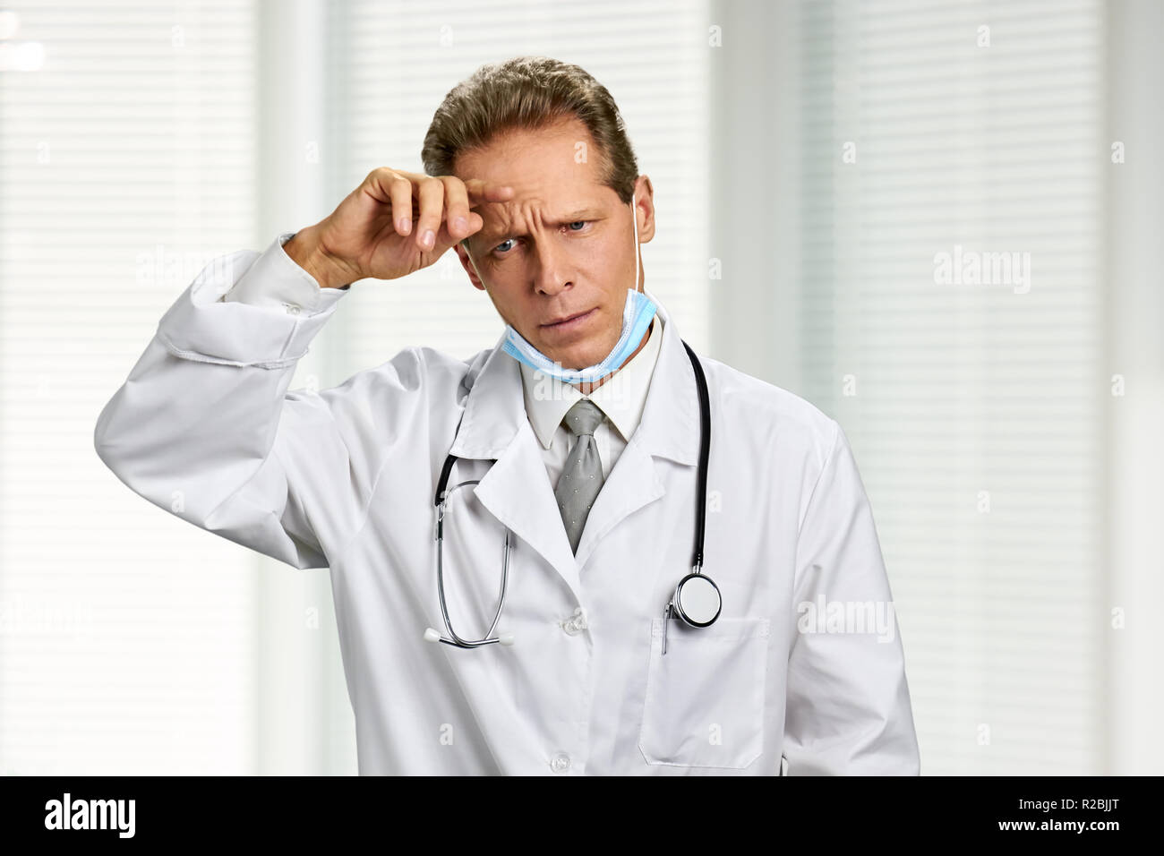 Portrait of upset male caucasian doctor. Mature doctor man touching his ...