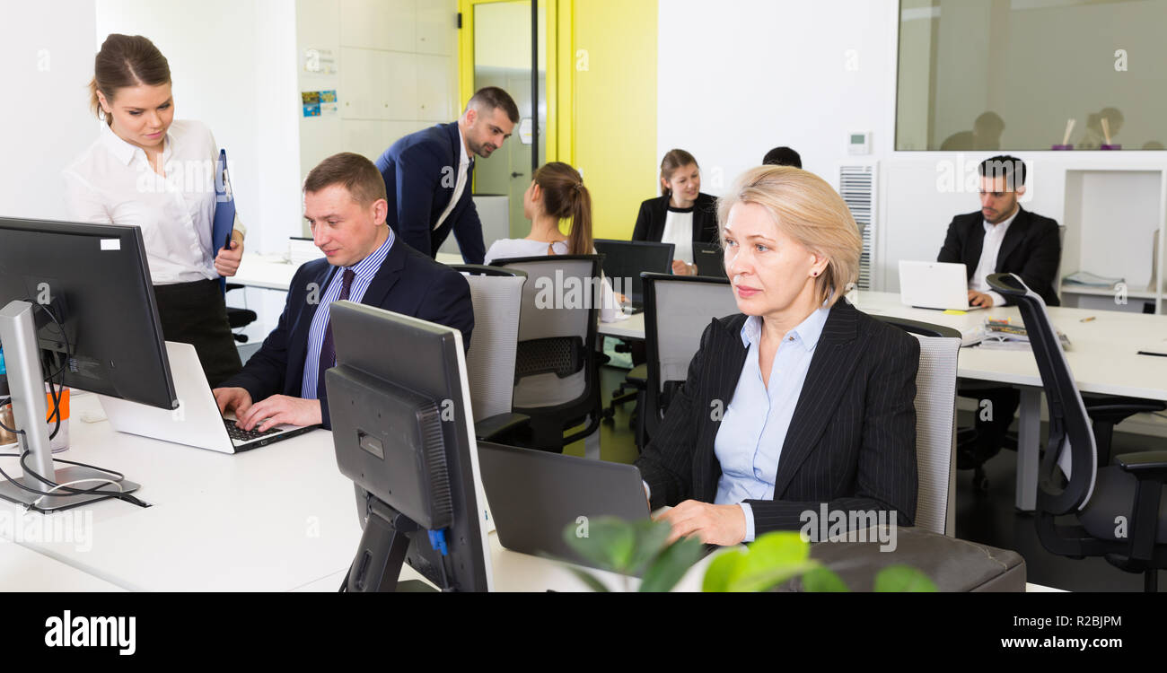 Successful coworkers engaged in business activities in busy open plan ...