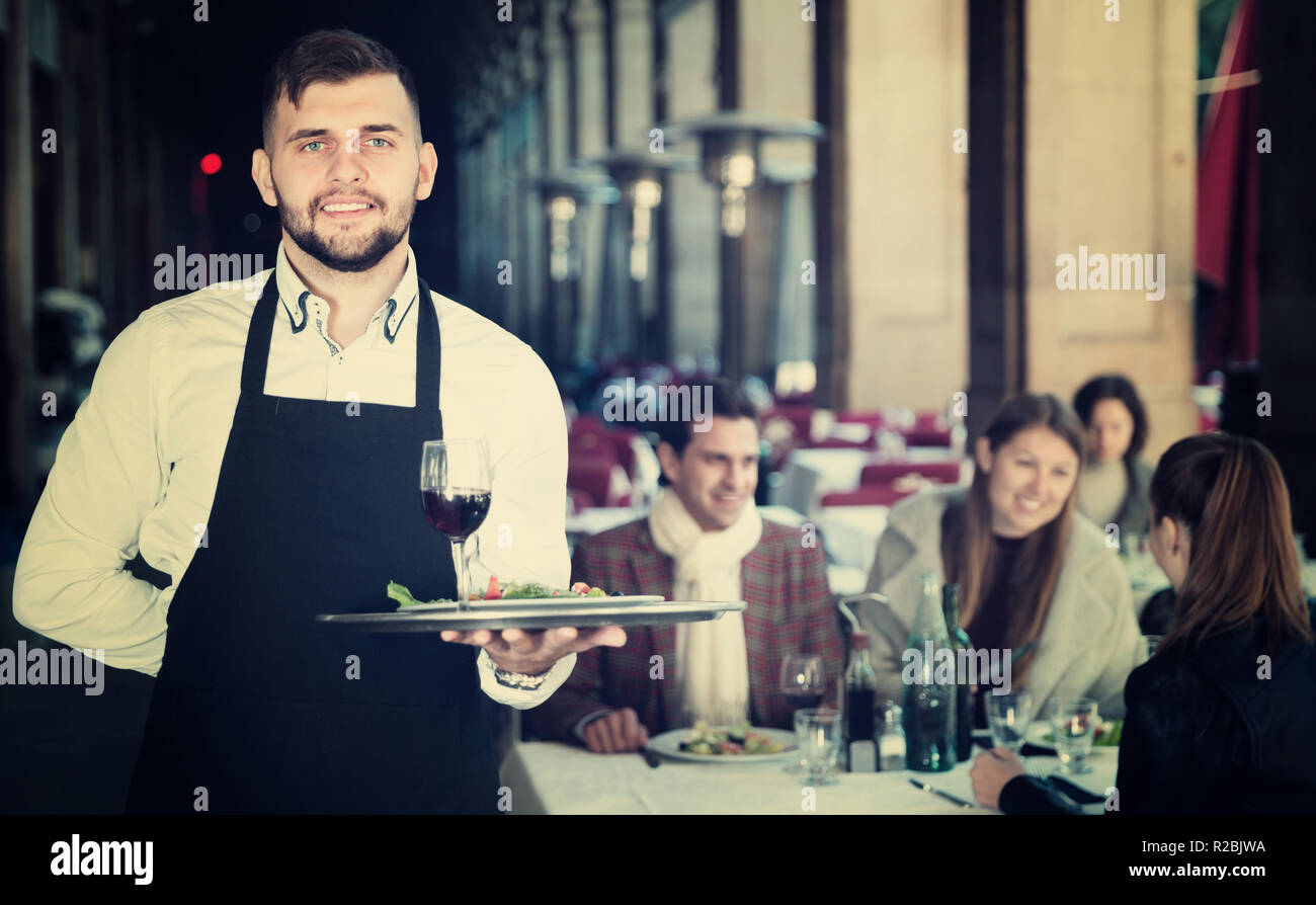 Portrait of glad cheerful positive smiling waiter with serving tray ...