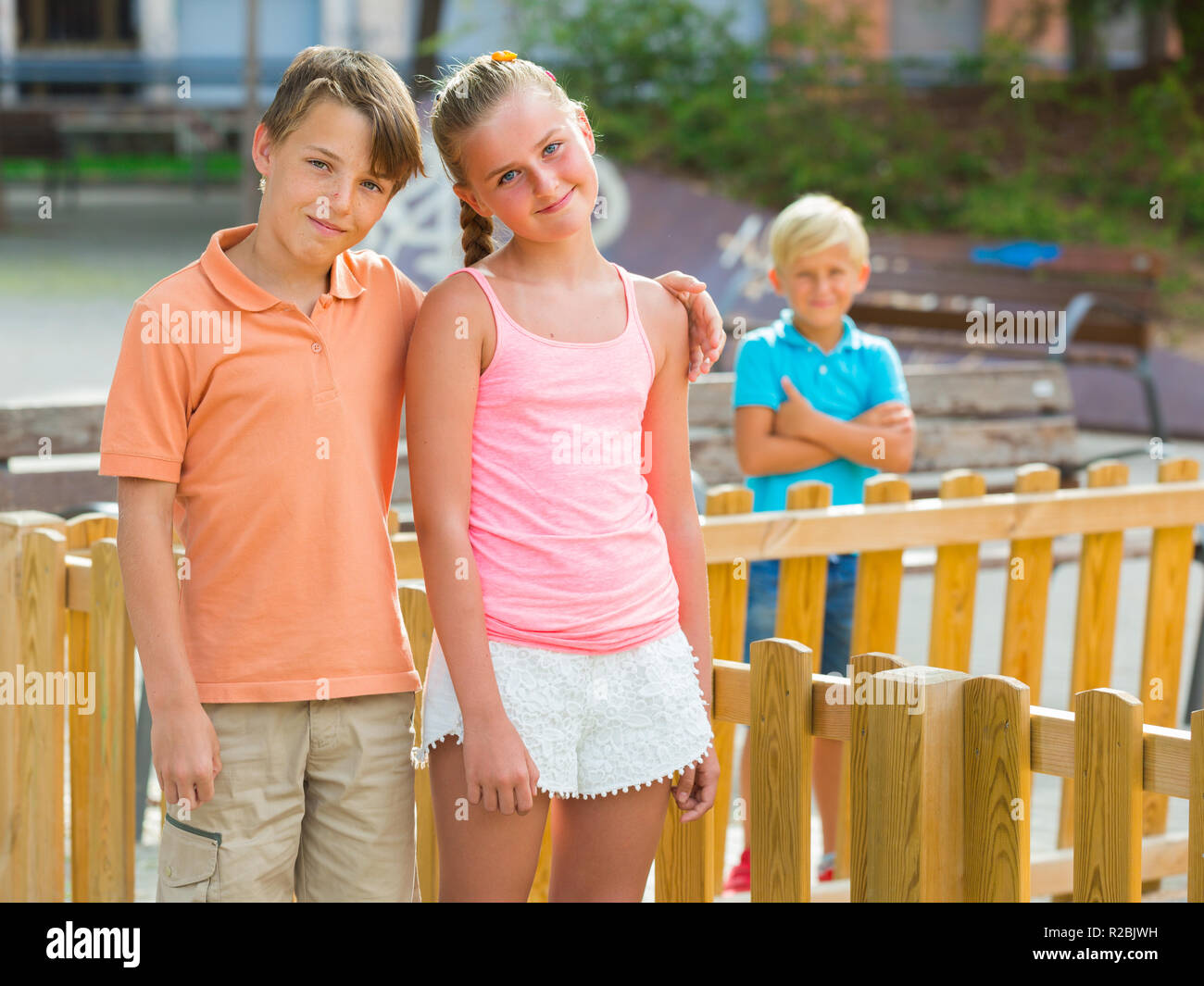 Smiling girl and boy are walking while their friend feeling aggrieved ...