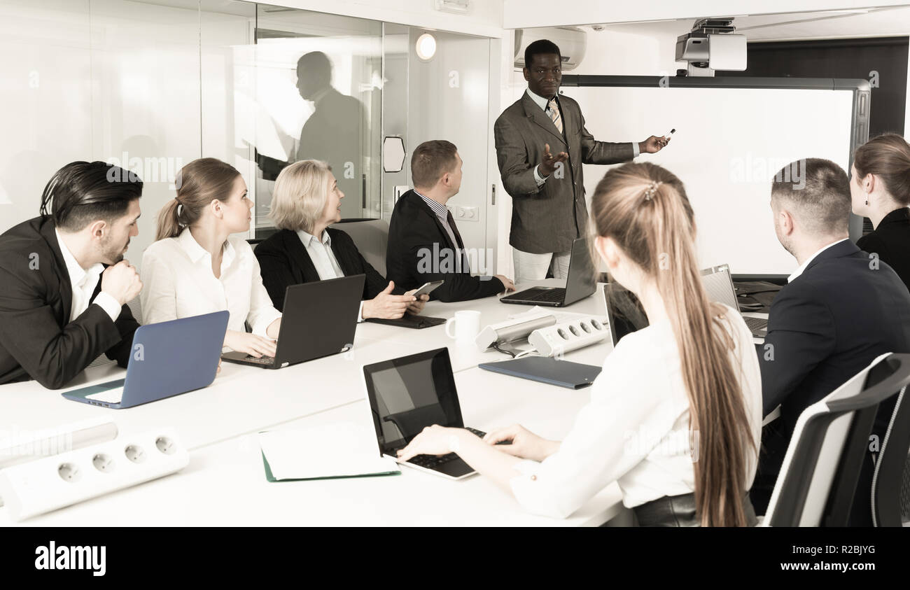 African American man giving presentation to colleagues at international ...