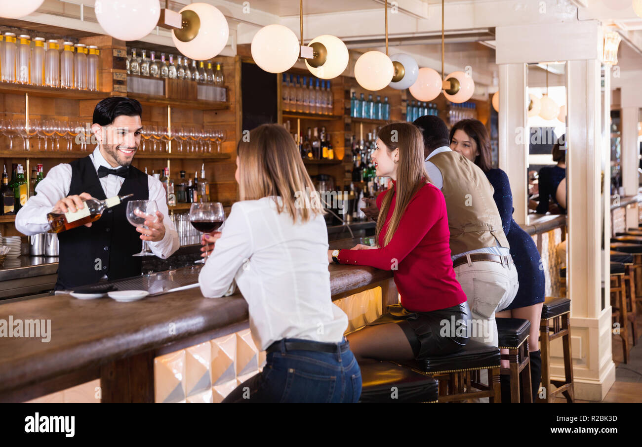 Portrait of smiling barman and happy people who are standing near bar ...