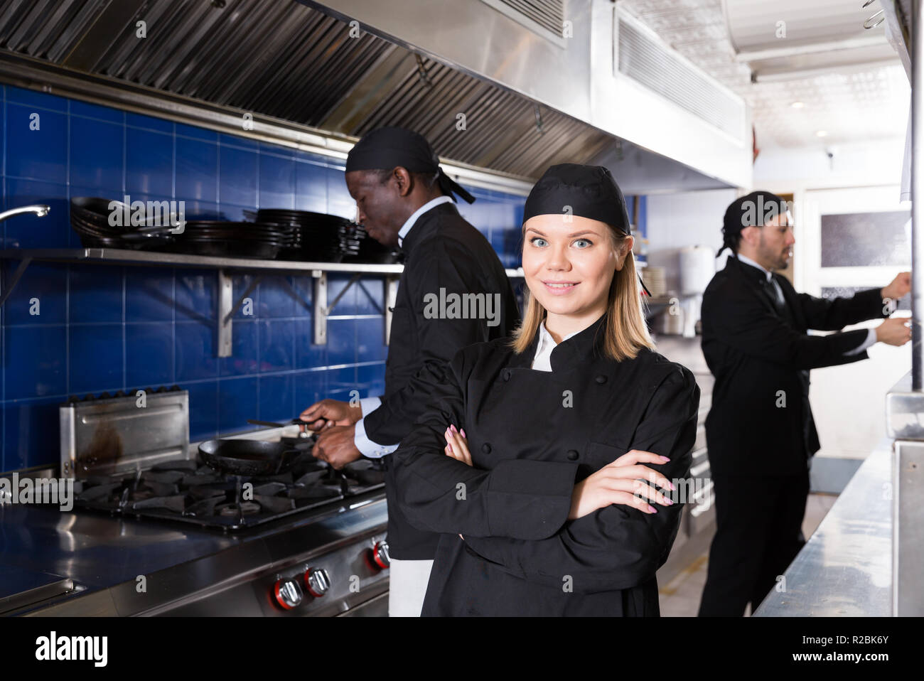 Portrait of confident young woman chef in modern restaurant kitchen ...