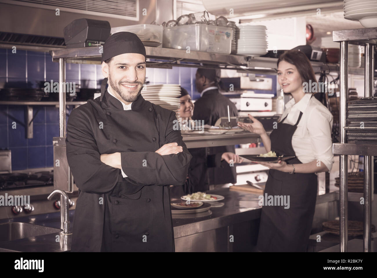 Portrait of handsome bearded chef standing in kitchen of restaurant ...