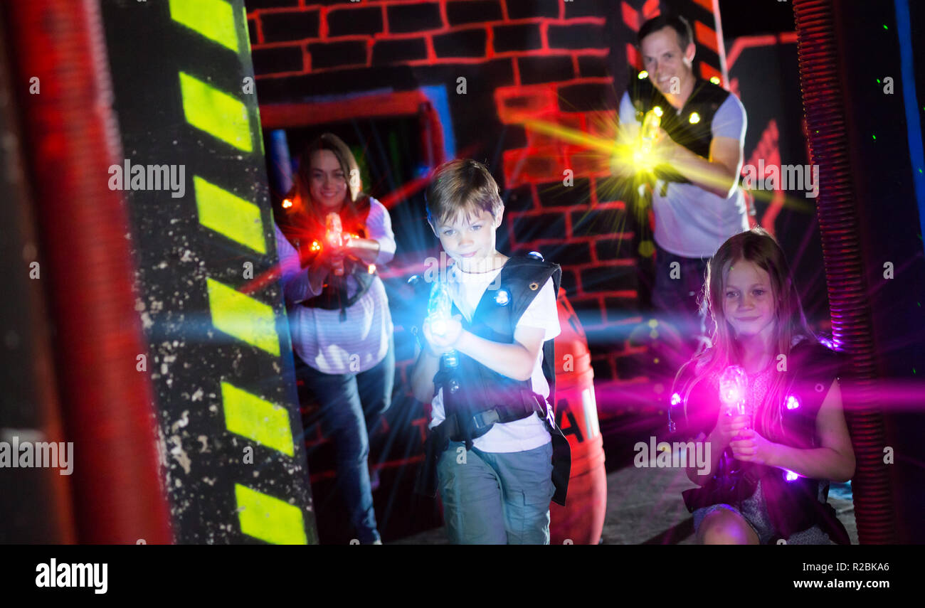 Portrait of excited kids in bright beams of laser guns during laser tag ...