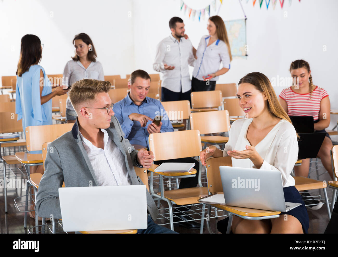 Happy group of adult students lively chatting while enjoying free time ...