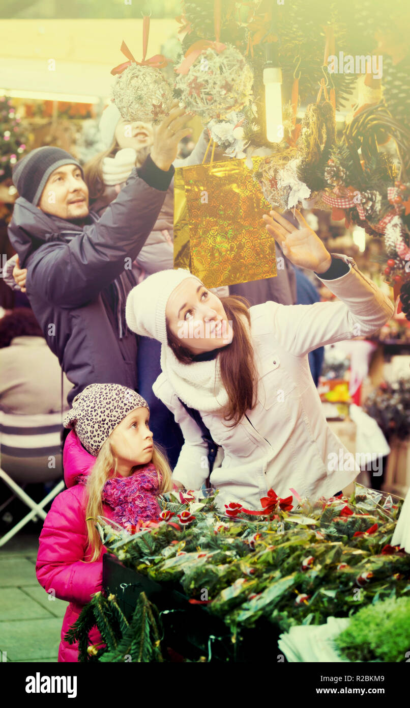 Young positive family of four choosing floral decorations at market ...