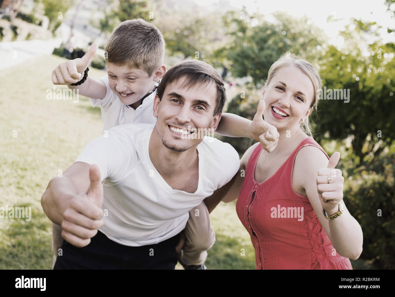 Portrait of smiling family with boy sitting on father's back hugging ...