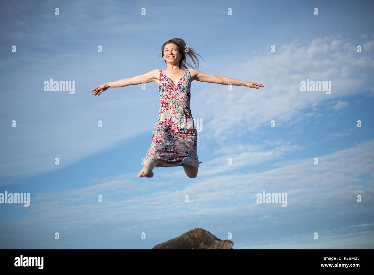 Pretty young female jumping background blue sky Stock Photo - Alamy