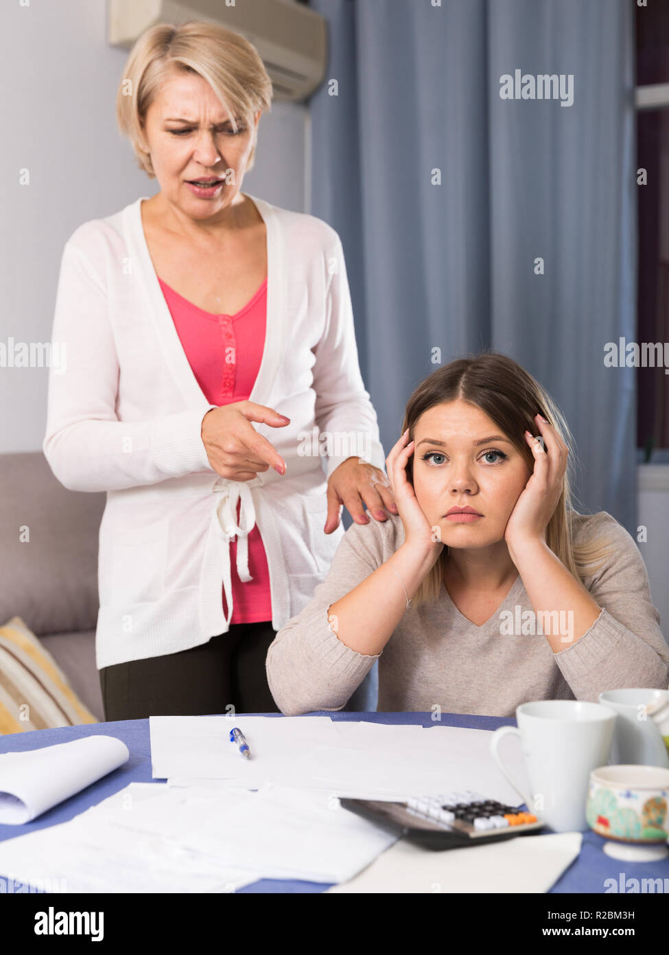 Angry mother is arguing with her daughter, who has a lot of financial ...