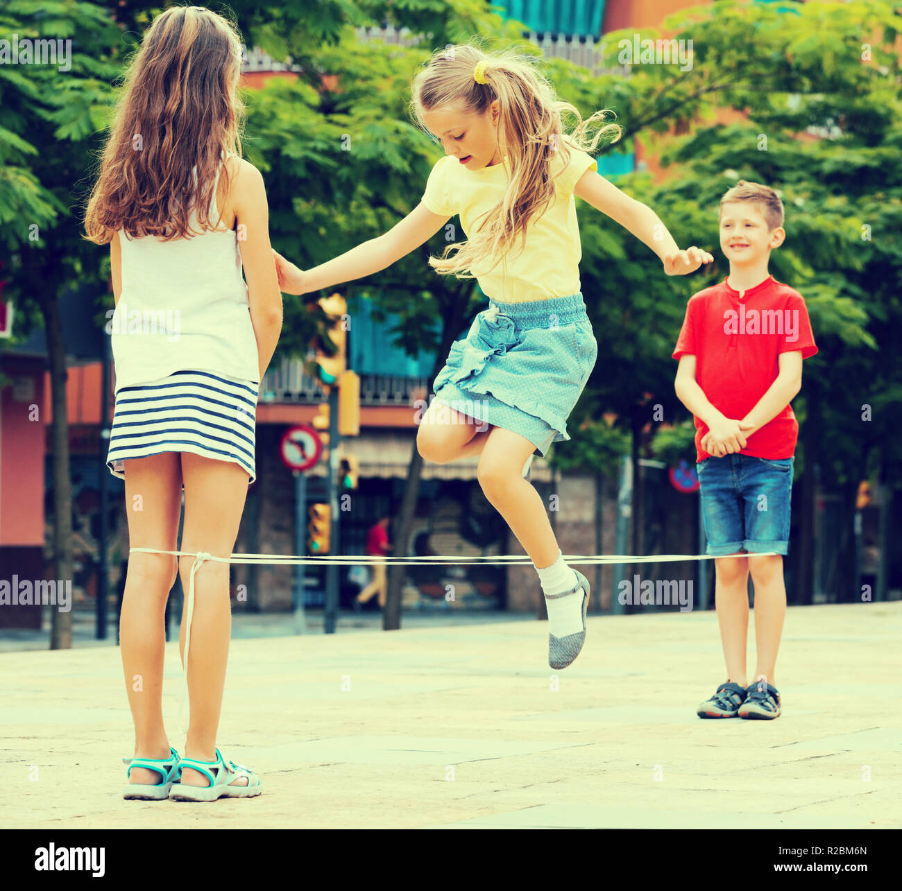 Portrait of group kids skipping on elastic jumping rope outdoor in ...