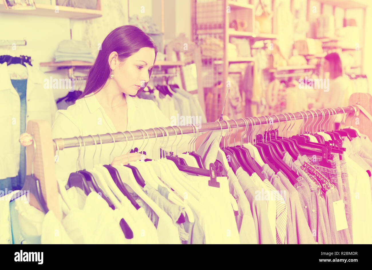 Portrait of woman customer choosing blue blouse in the fashion store ...