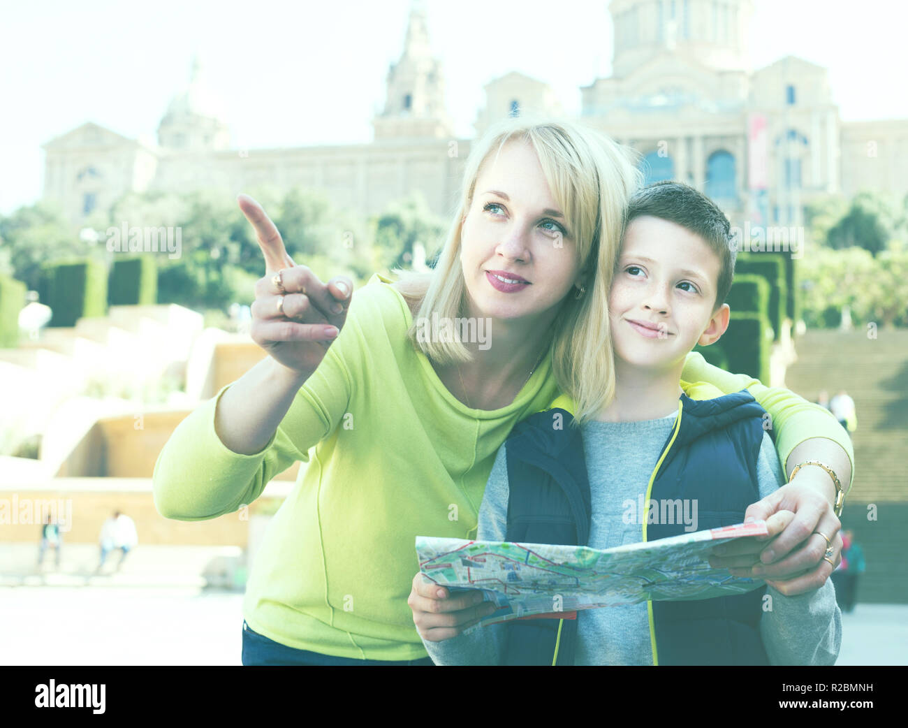 Smiling young mother and son reading map guide during sightseeing tour ...