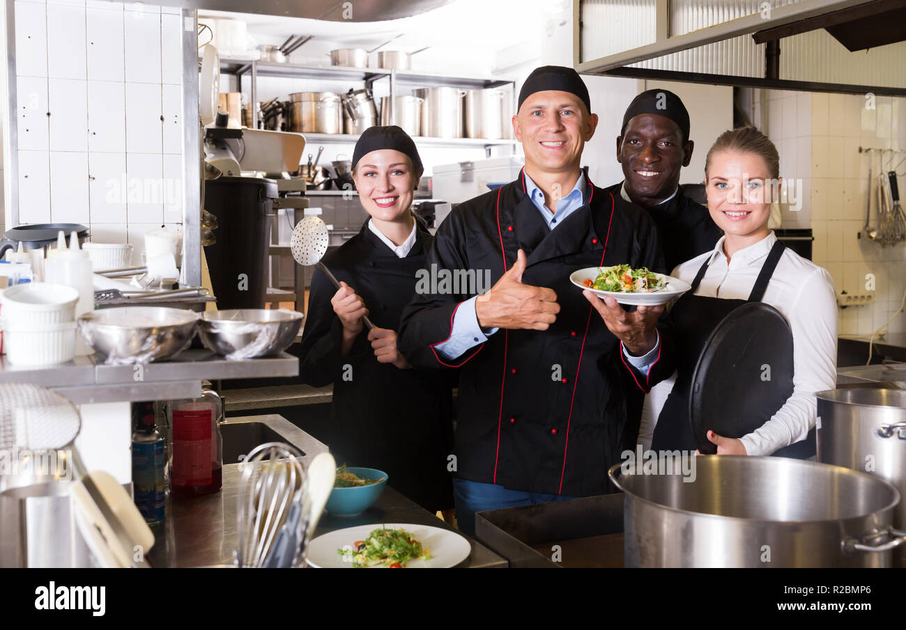 Portrait of confident smiling team of chefs in interior of restaurant ...