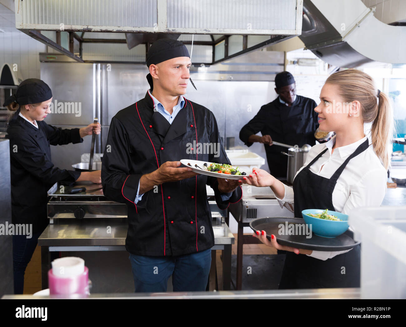 Staff of restaurant with head chef working together in kitchen Stock ...