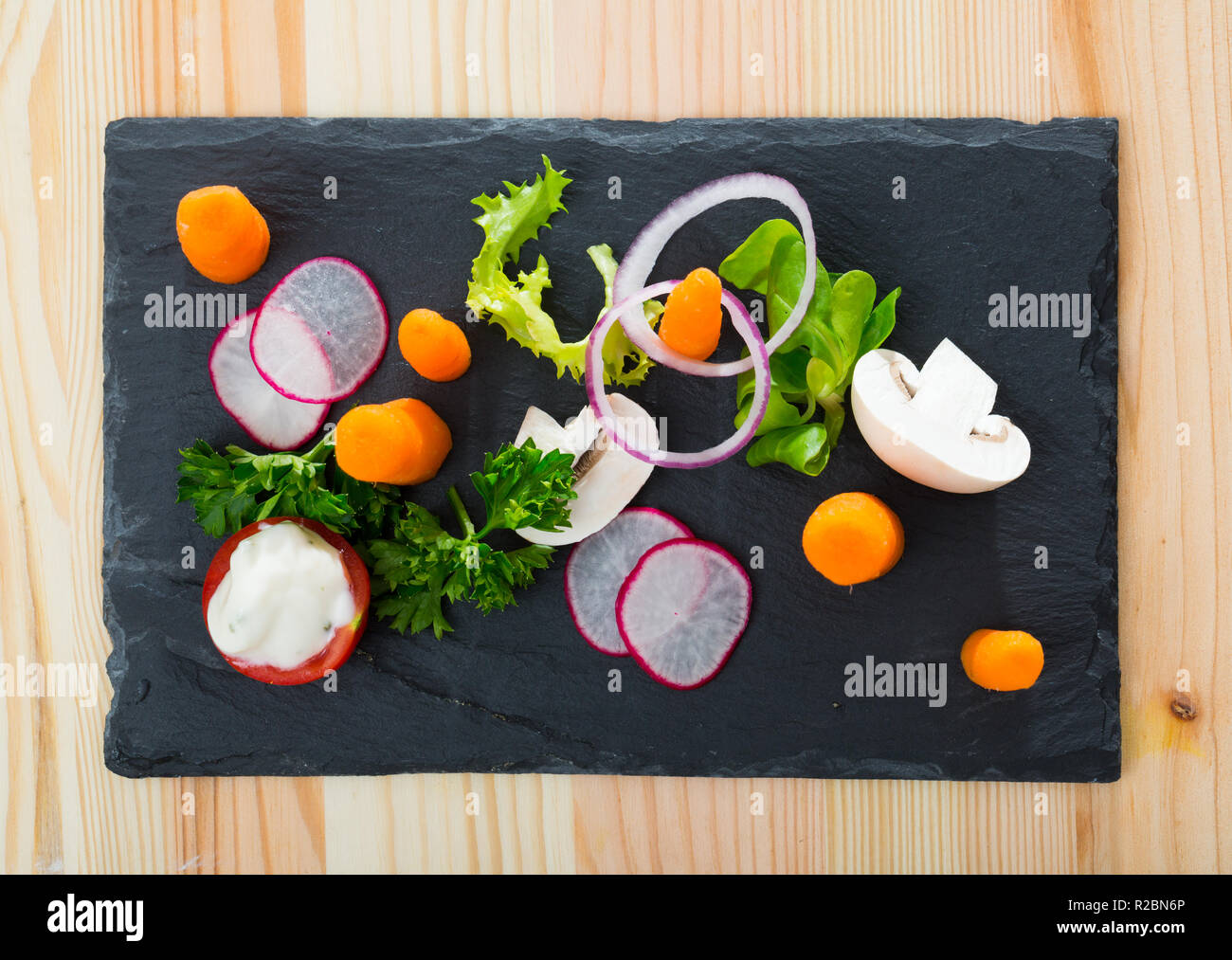 Colorful fresh vegetables on slate board - baby carrots, mushrooms ...