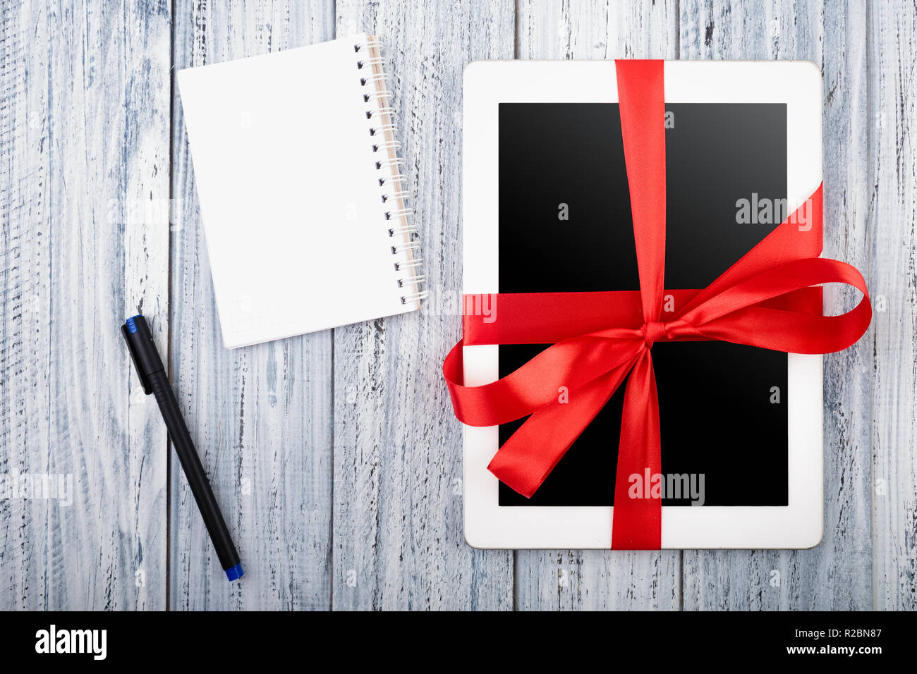 tablet wrapped in red ribbon, paper notebook, pen on white vintage ...