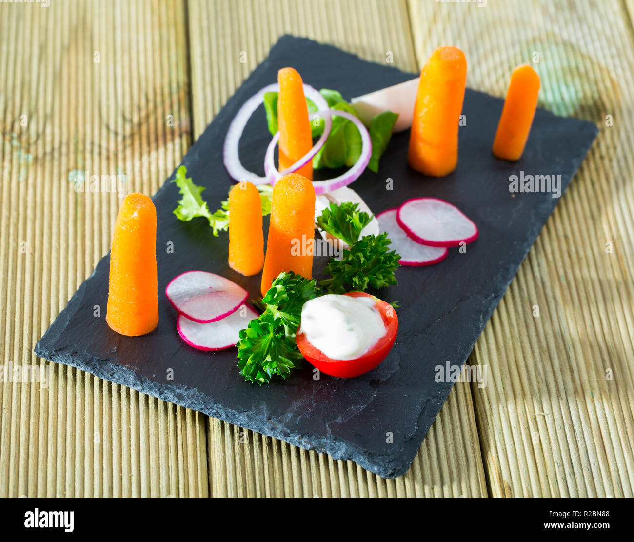 Colorful fresh vegetables on slate board - baby carrots, mushrooms ...