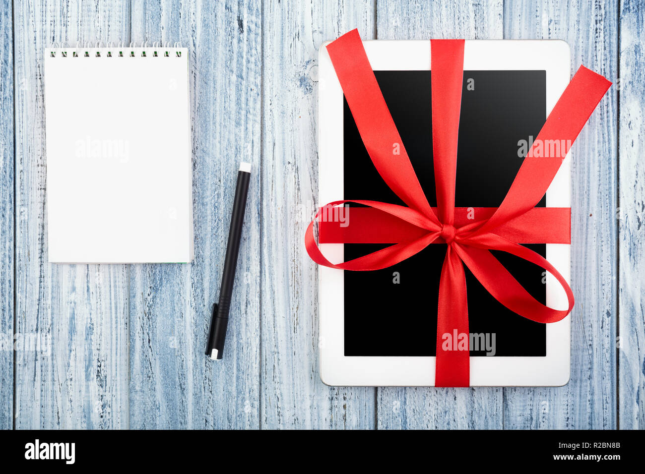 tablet wrapped in red ribbon, paper notebook, pen on white vintage ...